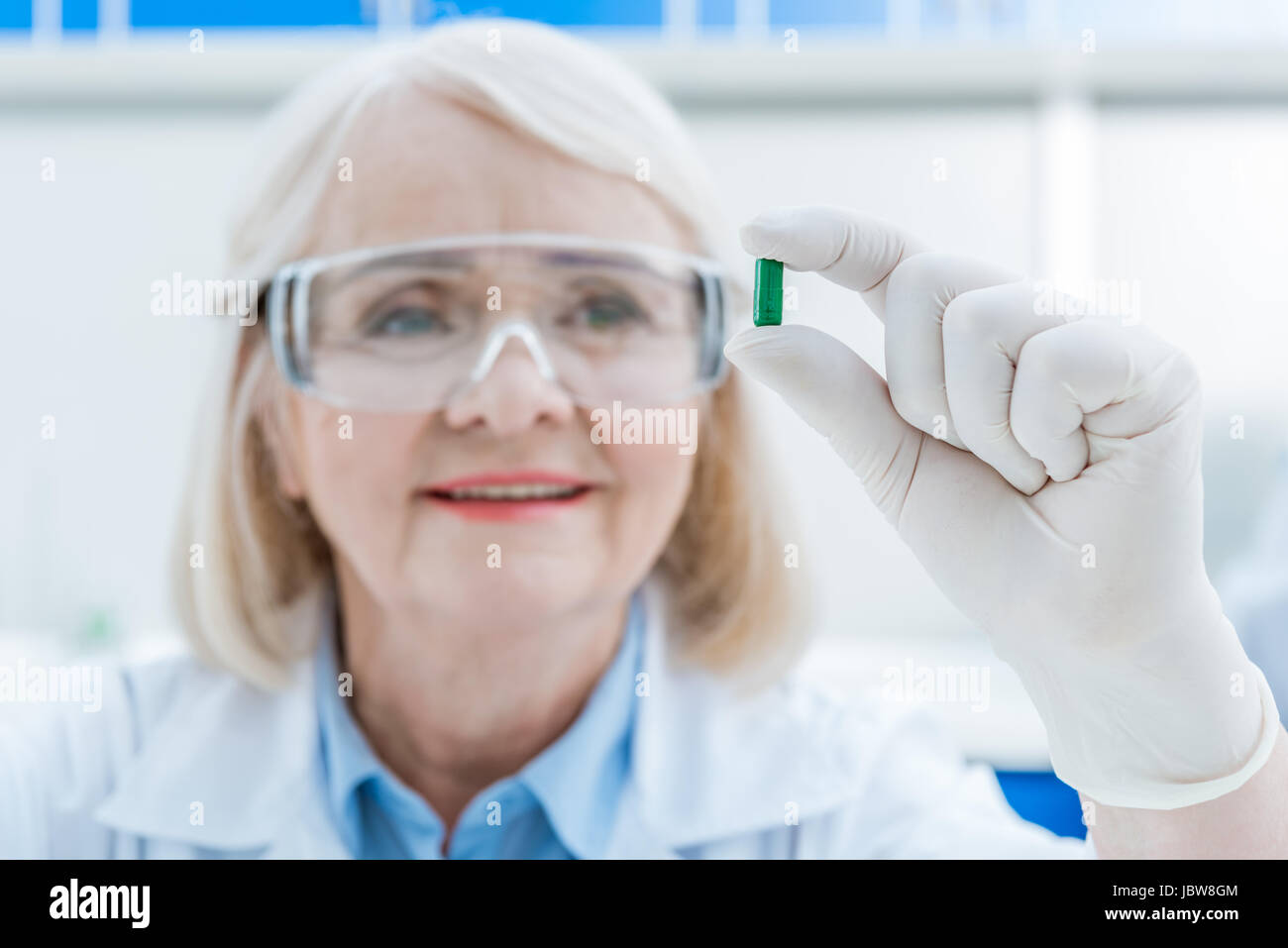 portrait of senior woman scientist analyzing pill in hand in lab Stock ...
