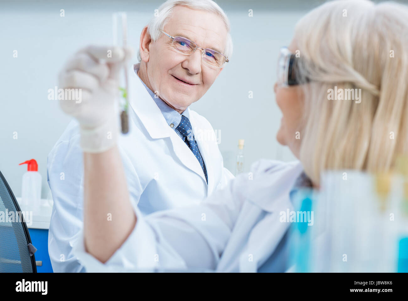 senior man scientist looking at test tube in colleague hand Stock Photo ...