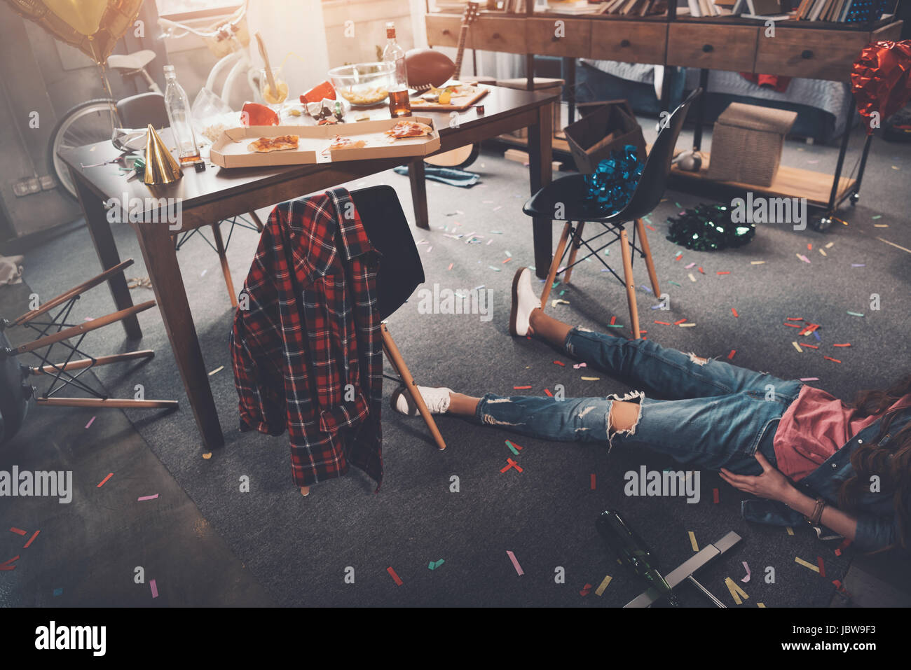 Cropped shot of drunk young woman lying on floor in messy room after ...