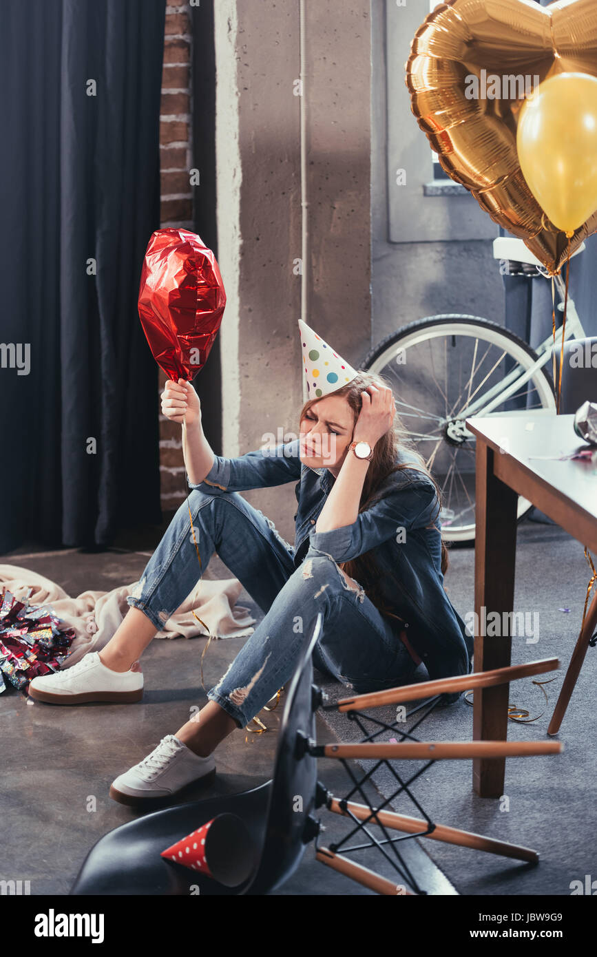 confused young woman holding balloon in messy room after party Stock ...