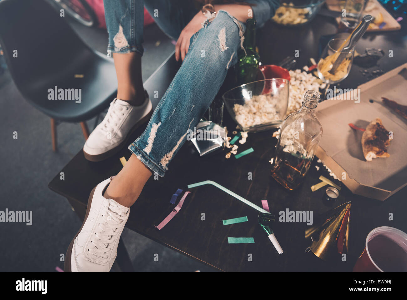 woman sitting on table in messy room after party Stock Photo - Alamy
