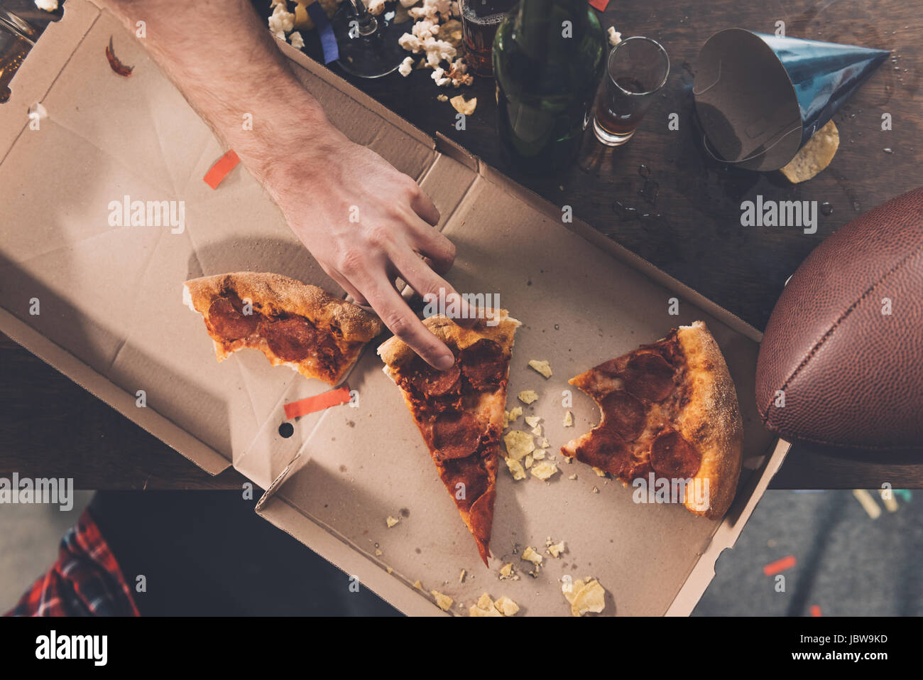 top view of man eating stale pizza in messy room after party Stock ...