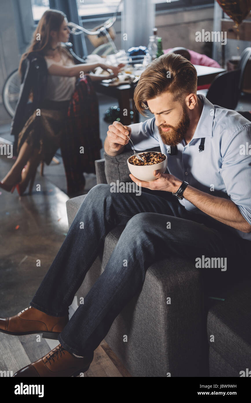 man eating corn flakes in messy room after party Stock Photo - Alamy