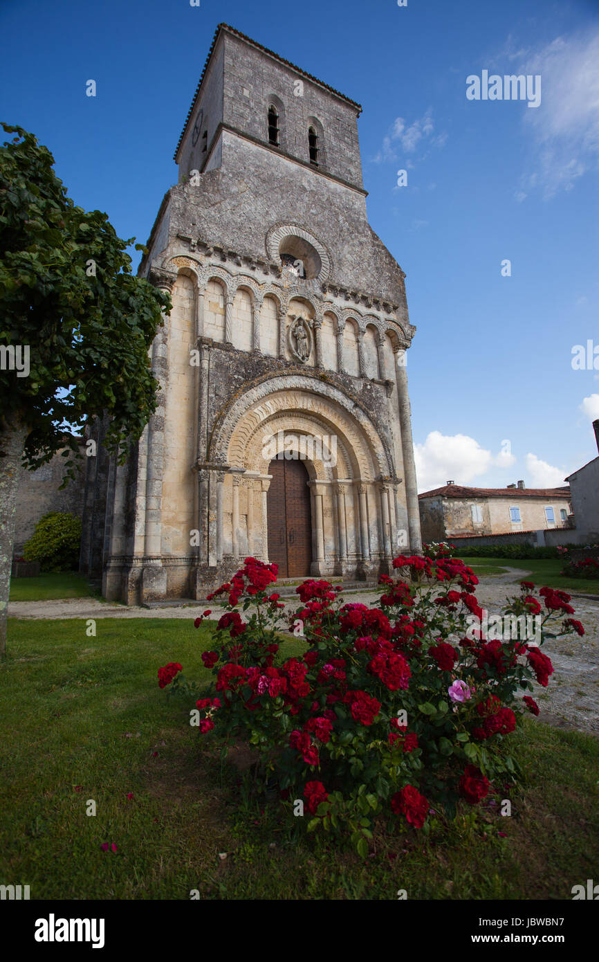 Facade of the romanesque Rioux church with red roses in the forefront ...
