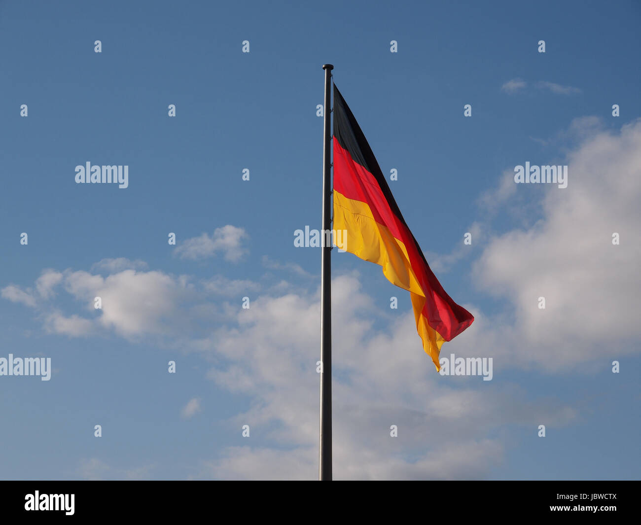 The national German flag of Germany over blue sky Stock Photo - Alamy