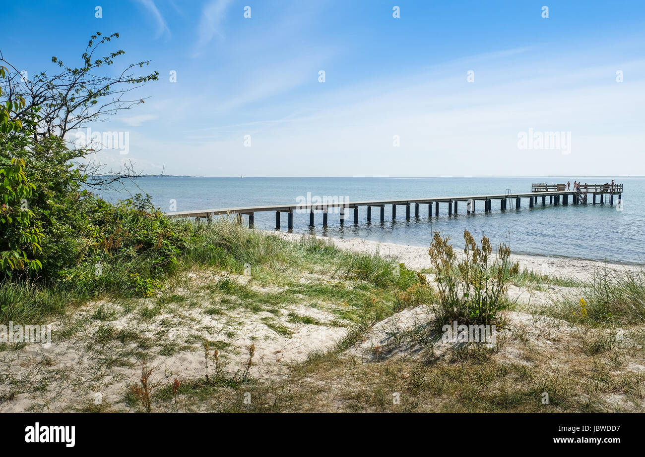 Idyllic beach with long pier at bright and warm summer day in southern ...