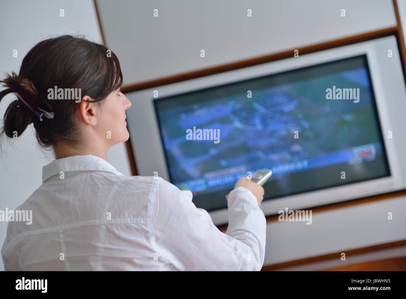 happy young woman watching tv at modern home livingroom Stock Photo - Alamy