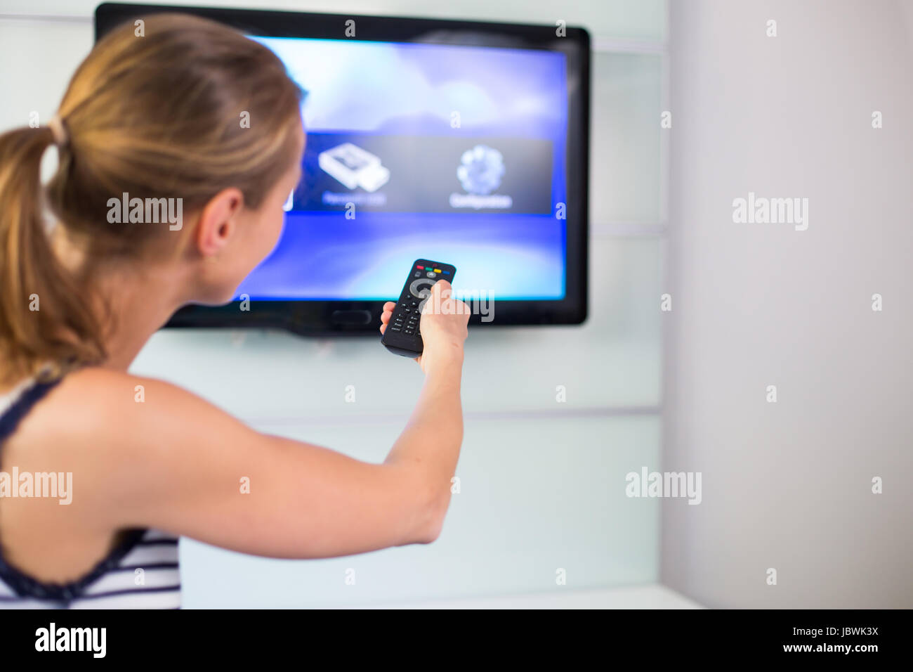 Young woman at home watching TV, turning it on, changing channels Stock ...