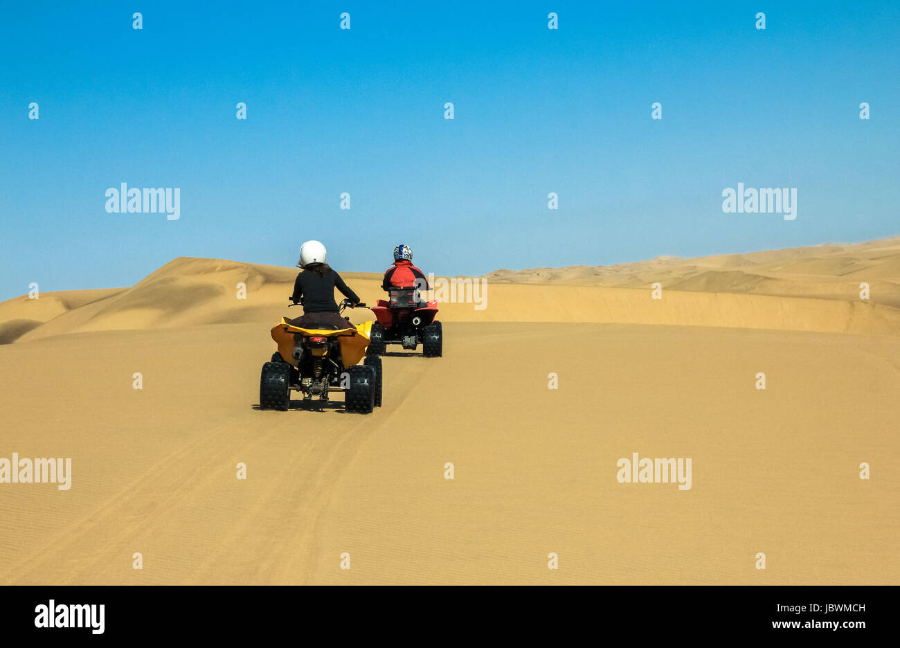 Two happy quad bikers driving in sand dunes. Young active couple in ...