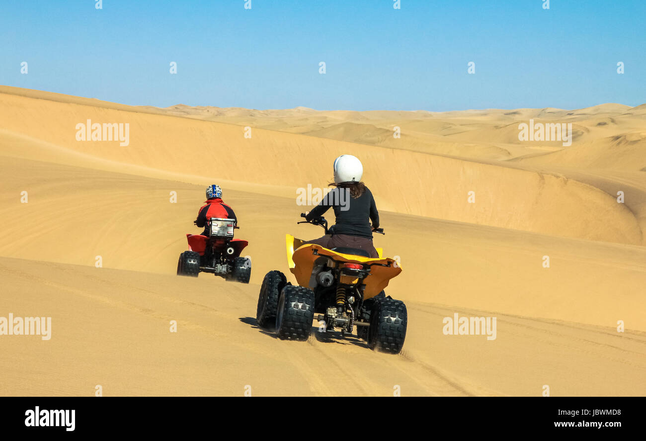 Two happy quad bikers driving in sand dunes. Young active couple in ...