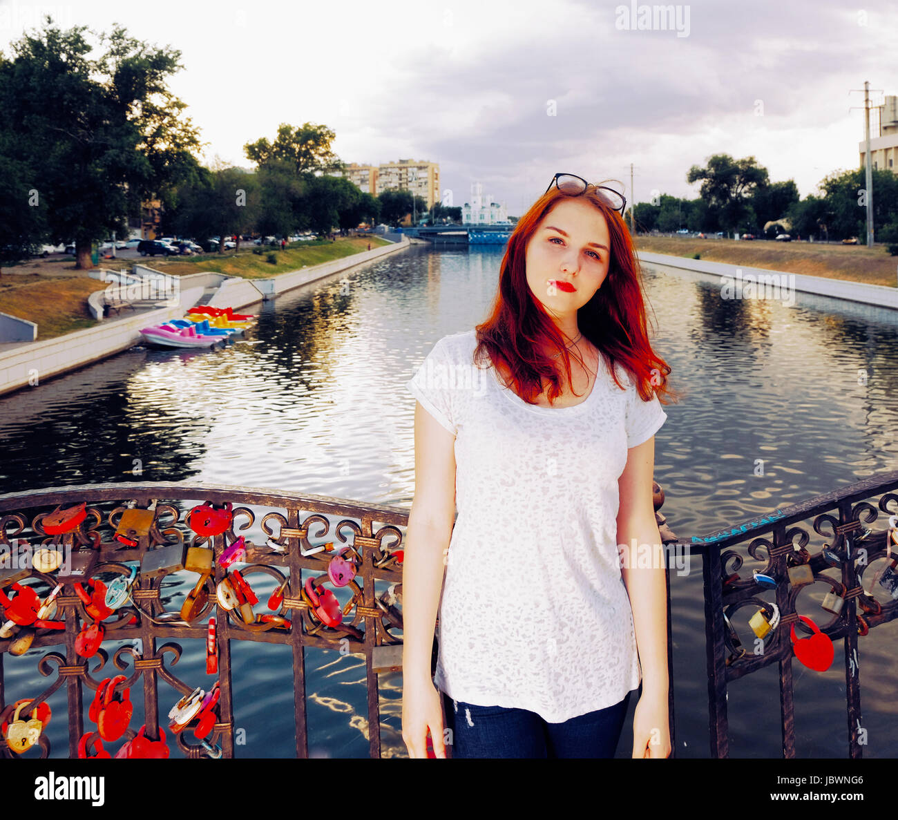 Ginger hair woman standing on the bridge of love with many locks ...