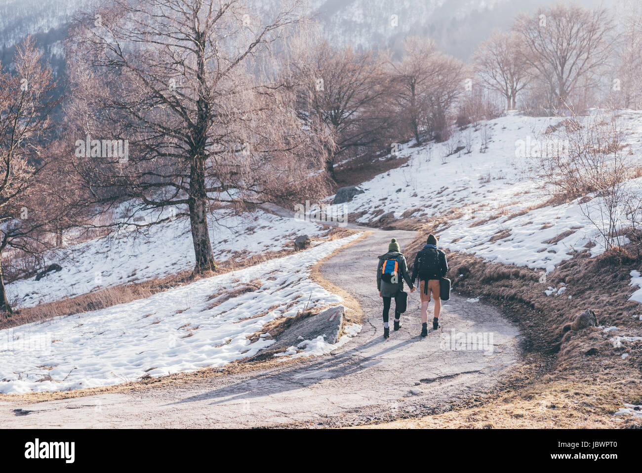 Rear view of hiking couple hiking along snowy rural road, Monte San ...