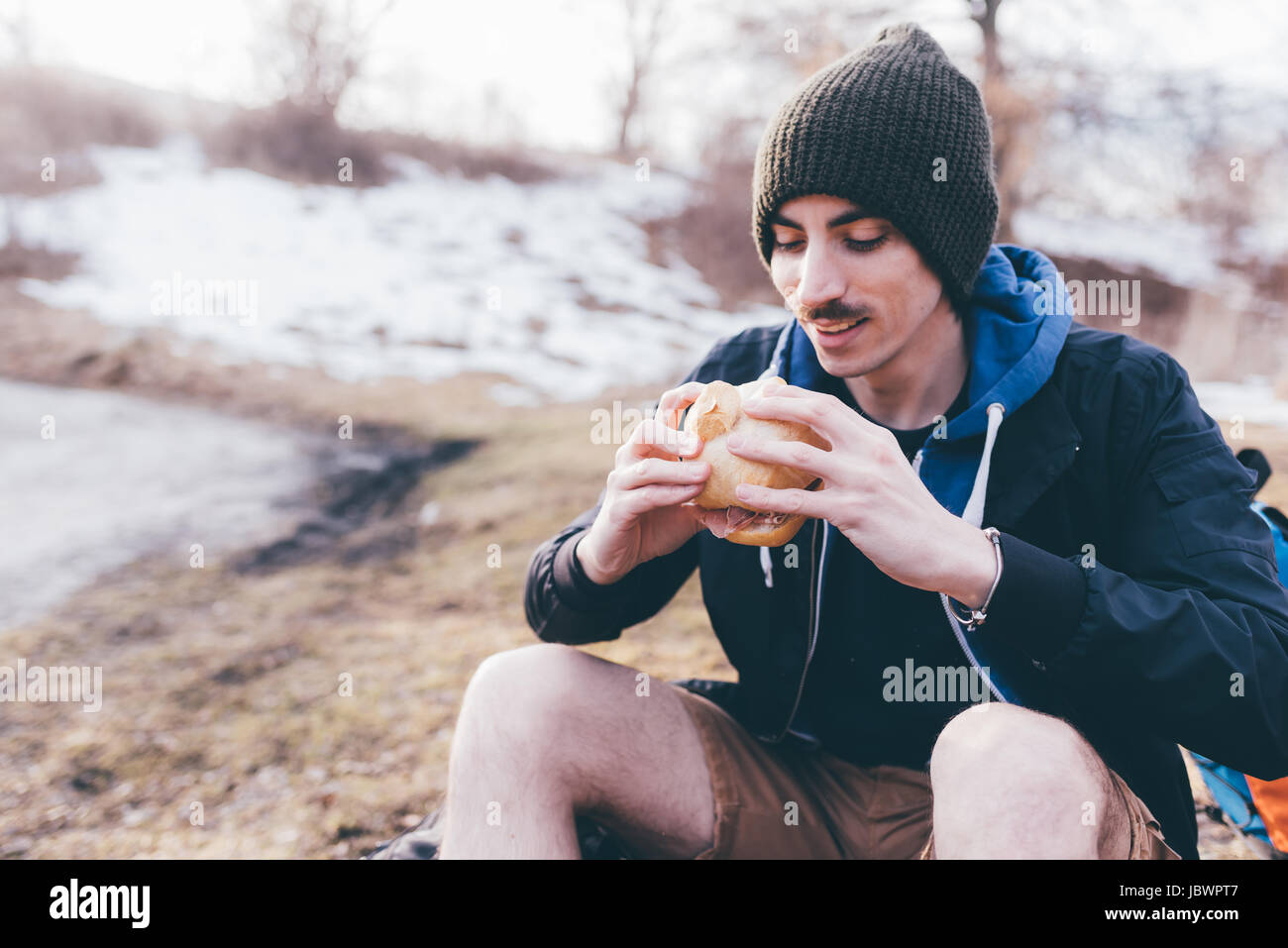 Young male hiker on roadside eating sandwich, Monte San Primo, Italy ...