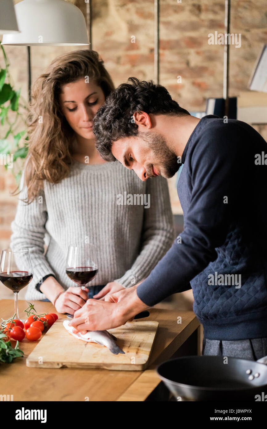 Young couple preparing fish at kitchen counter Stock Photo - Alamy