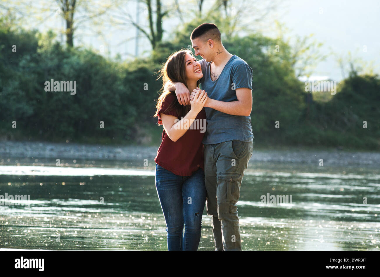 Romantic couple standing beside river, face to face, smiling Stock ...