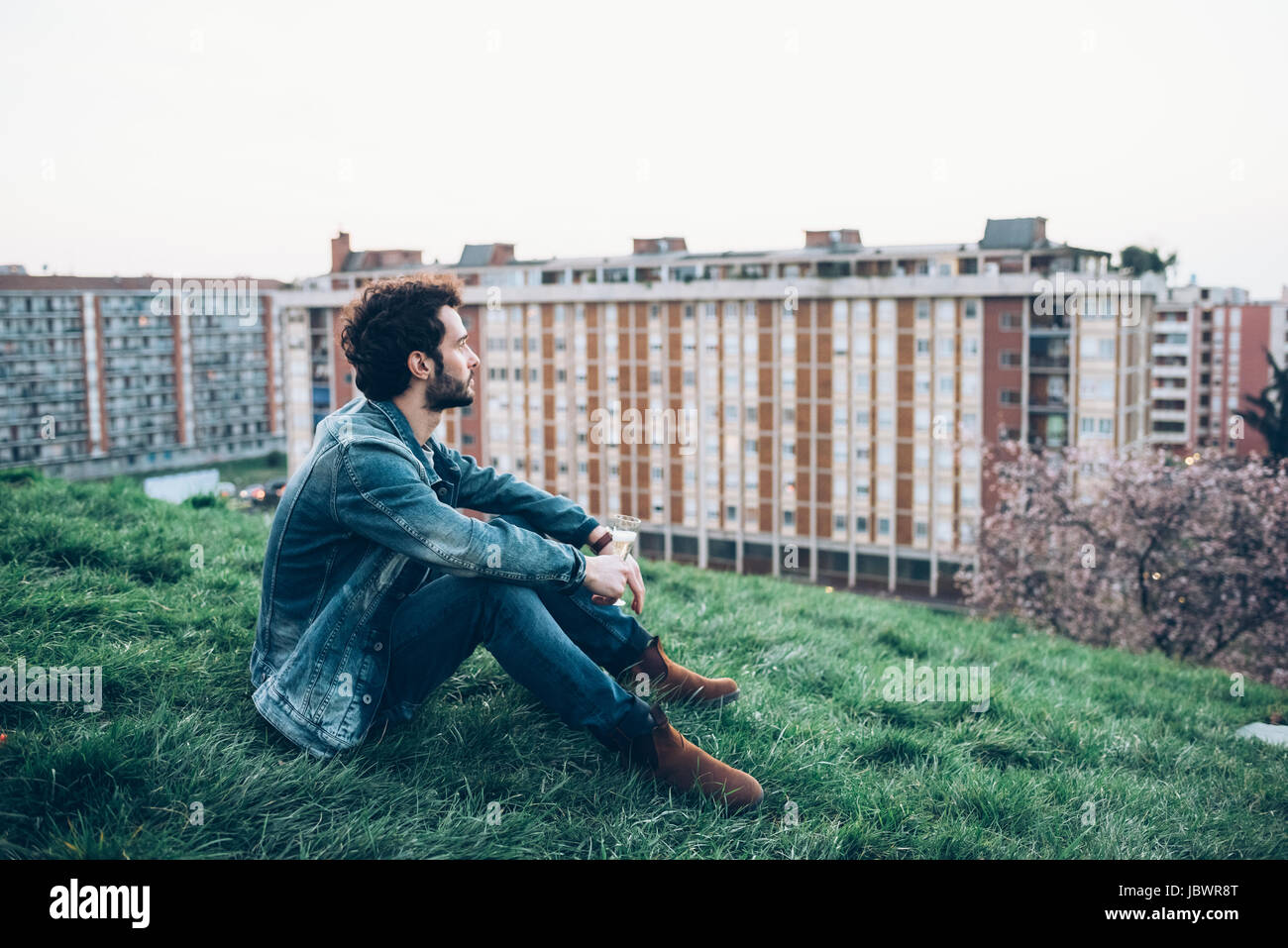 Young man sitting on rooftop garden, looking at view Stock Photo - Alamy