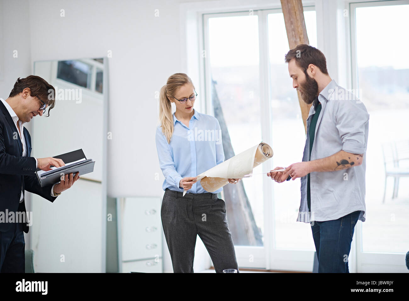 Interior design team looking at wall paper roll in design studio Stock ...