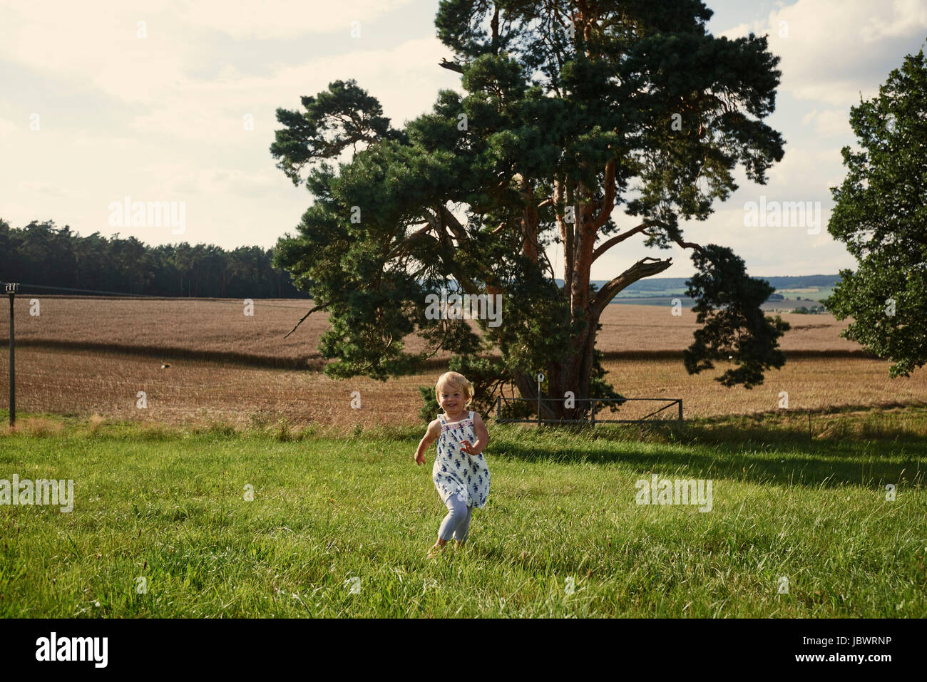 Female toddler running across field Stock Photo - Alamy