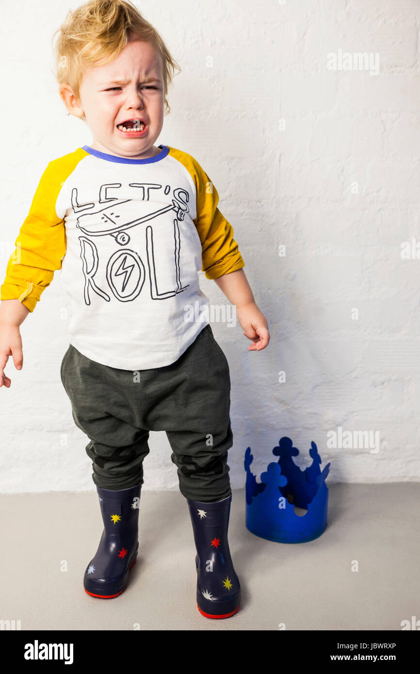 Male toddler standing next to toy crown crying Stock Photo - Alamy