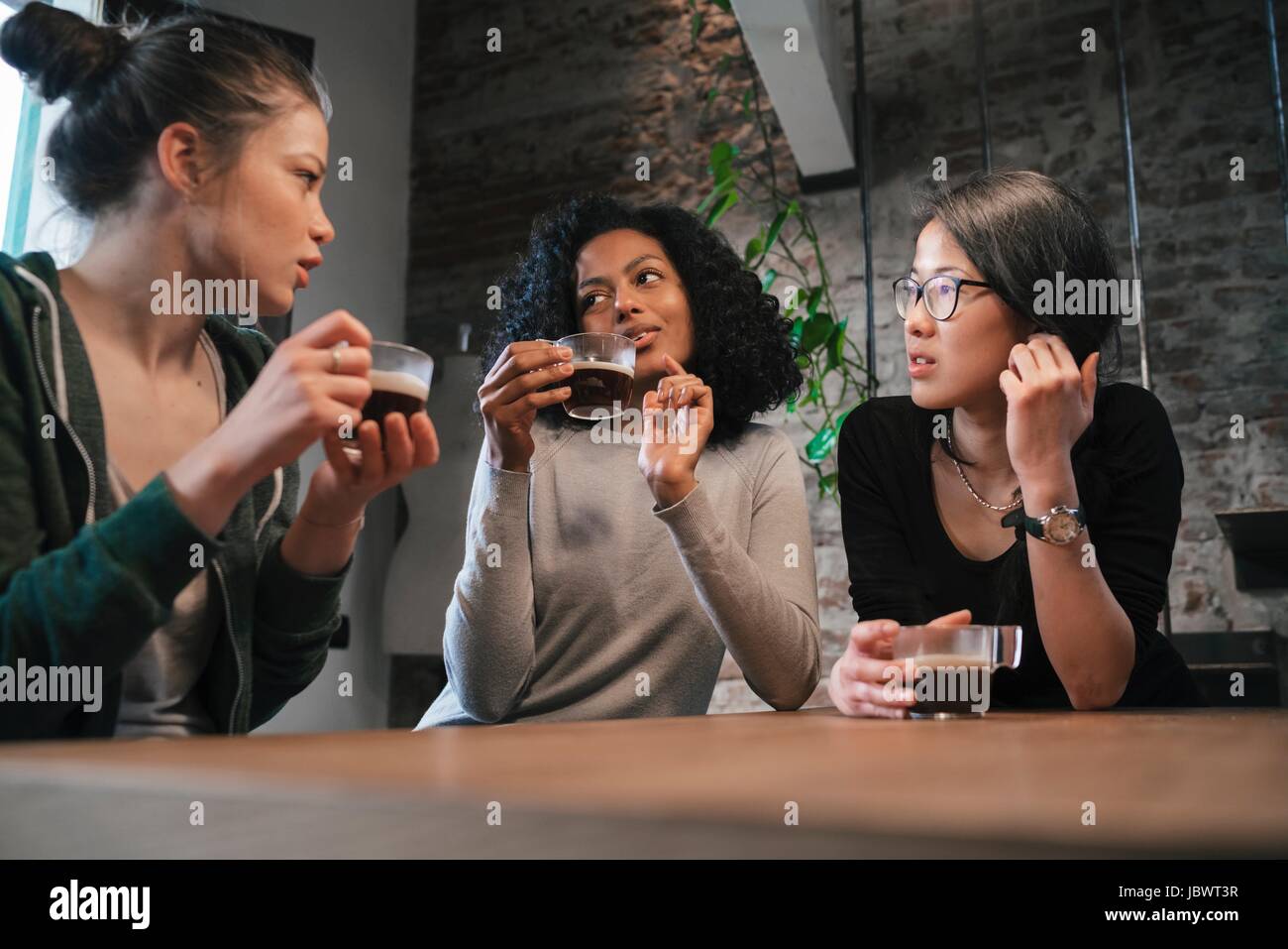 Friends drinking coffee chatting Stock Photo - Alamy