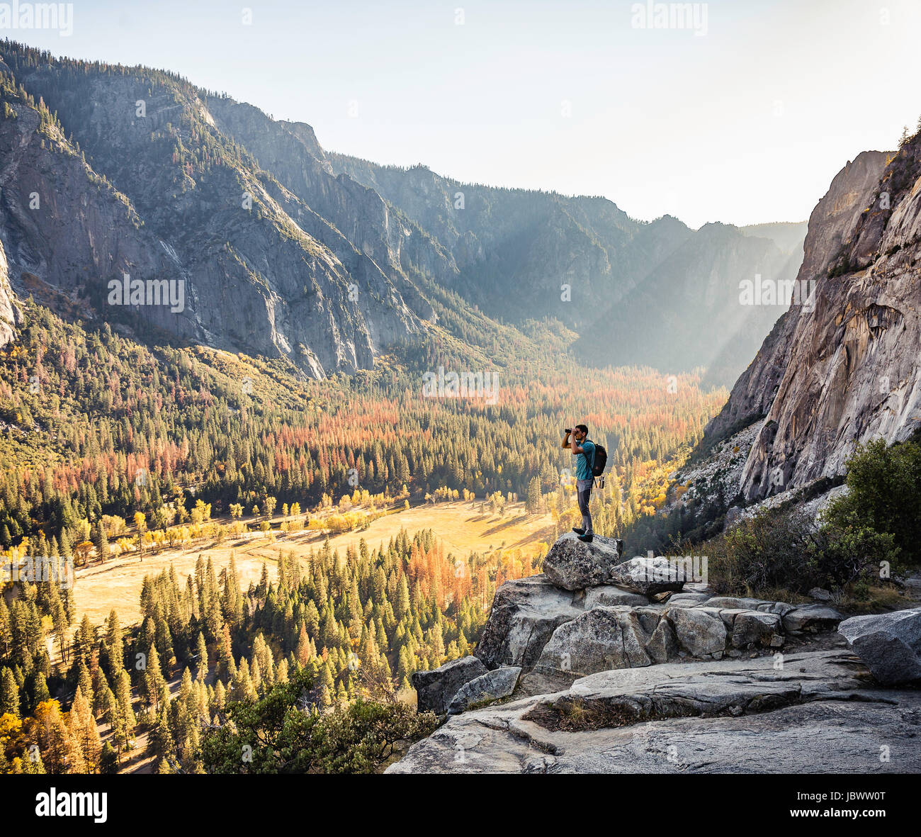 Man on rocky edge looking out through binoculars, Yosemite National Park, California, USA Stock ...