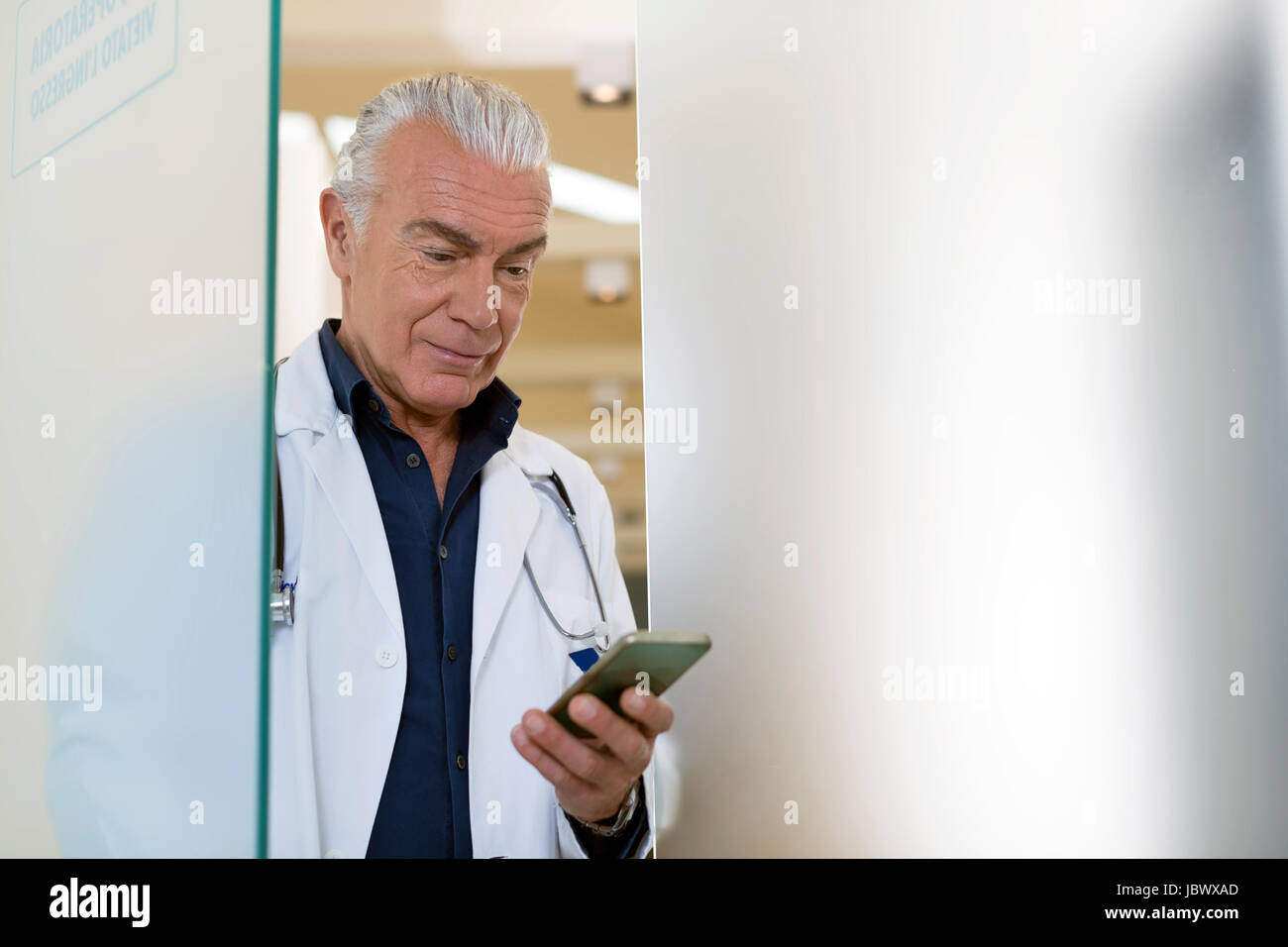 Doctor looking at mobile phone Stock Photo - Alamy