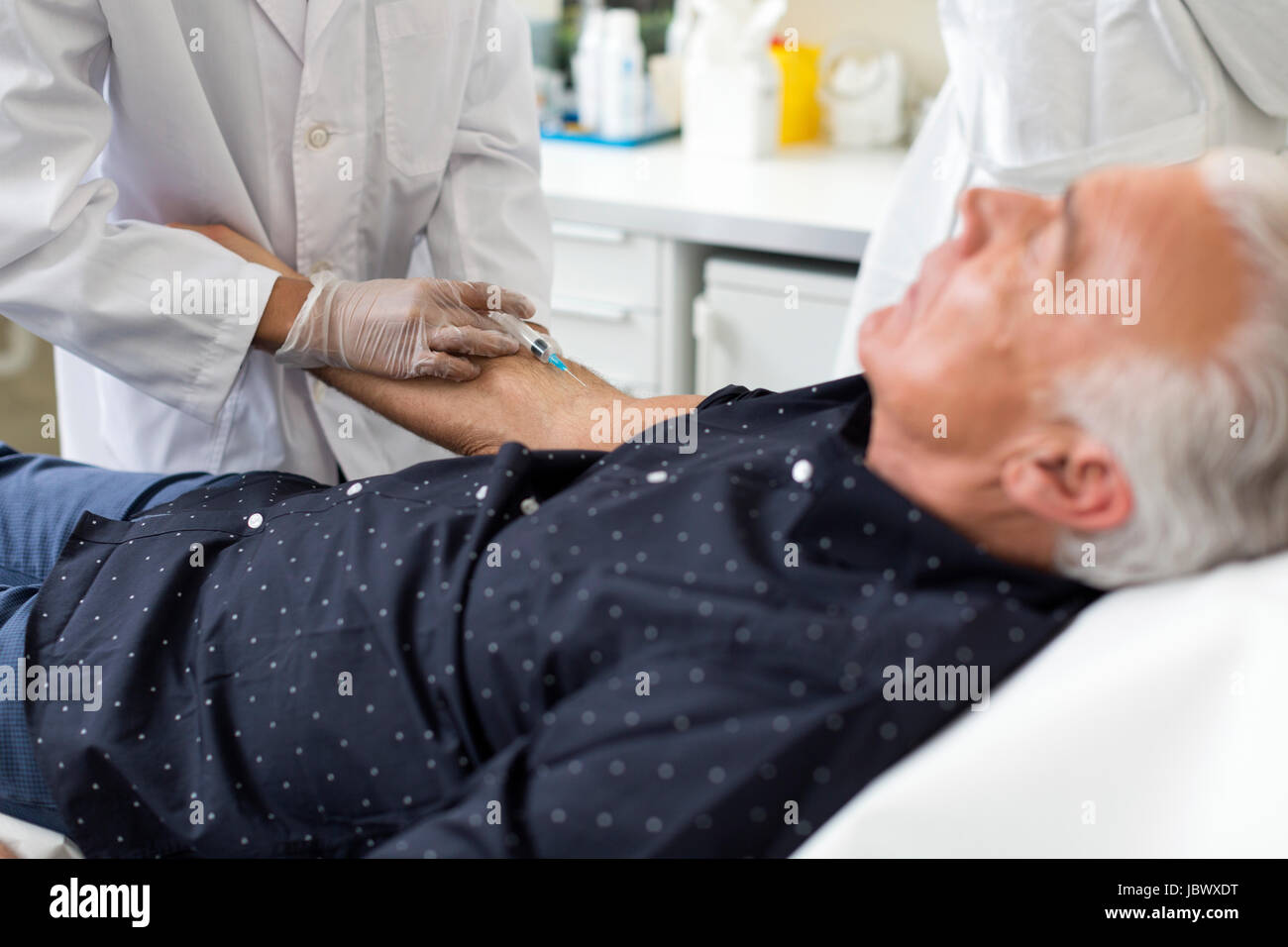 Doctor extracting patient's blood with syringe Stock Photo - Alamy