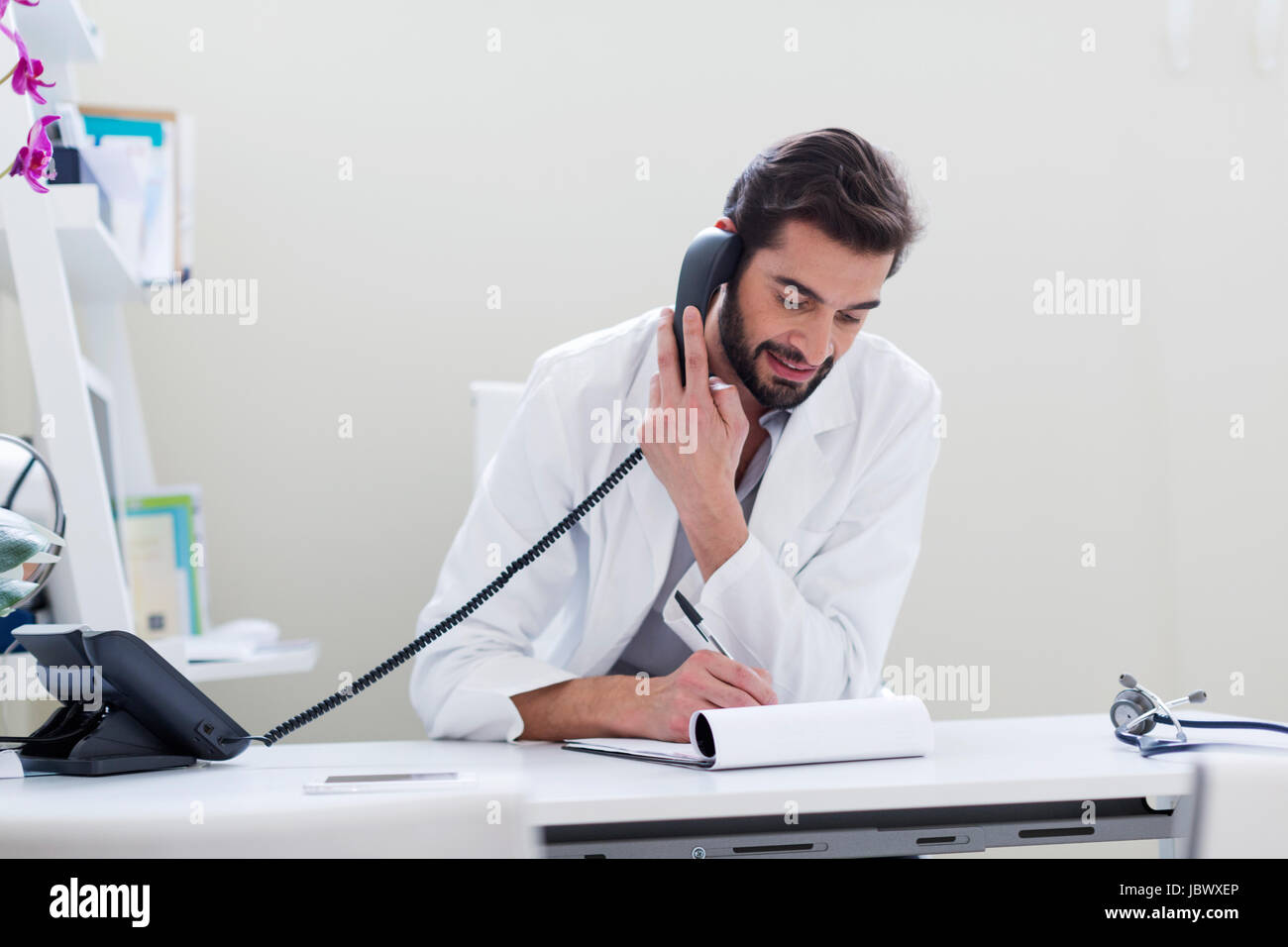Doctor at desk making telephone call Stock Photo - Alamy