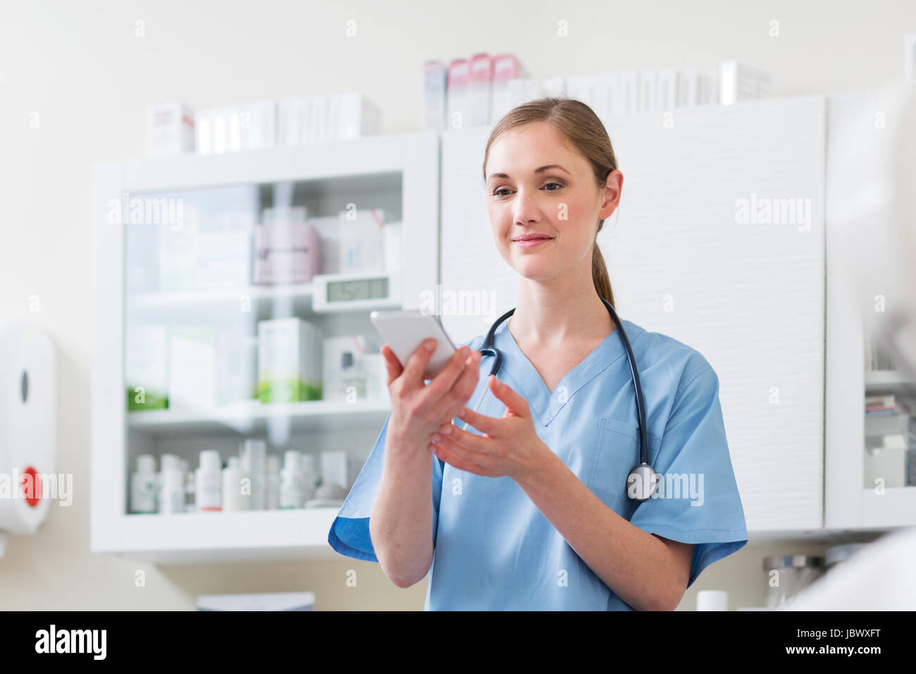 Doctor in hospital holding mobile phone looking at camera smiling Stock ...