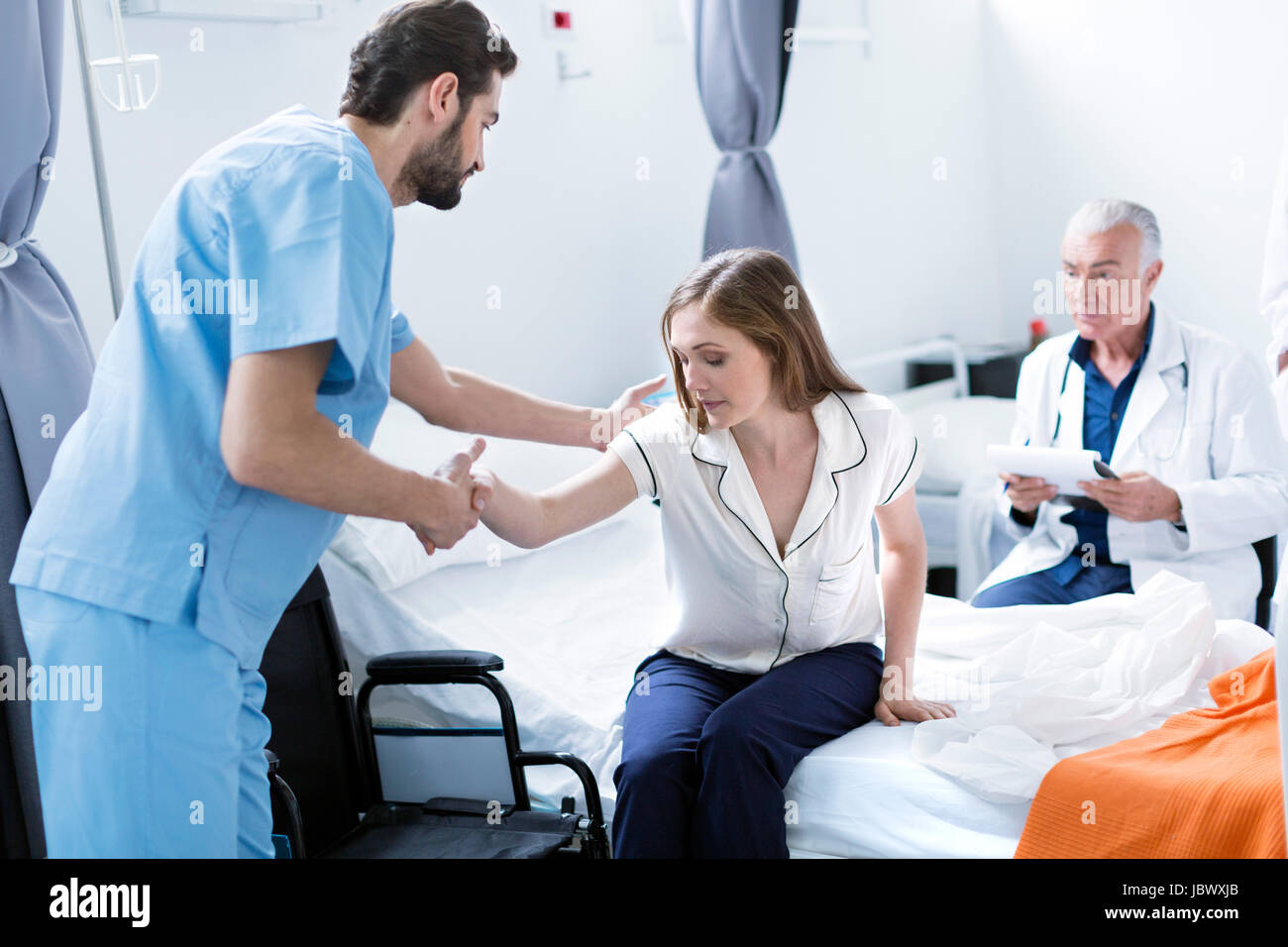 Doctor helping patient out of hospital bed Stock Photo - Alamy