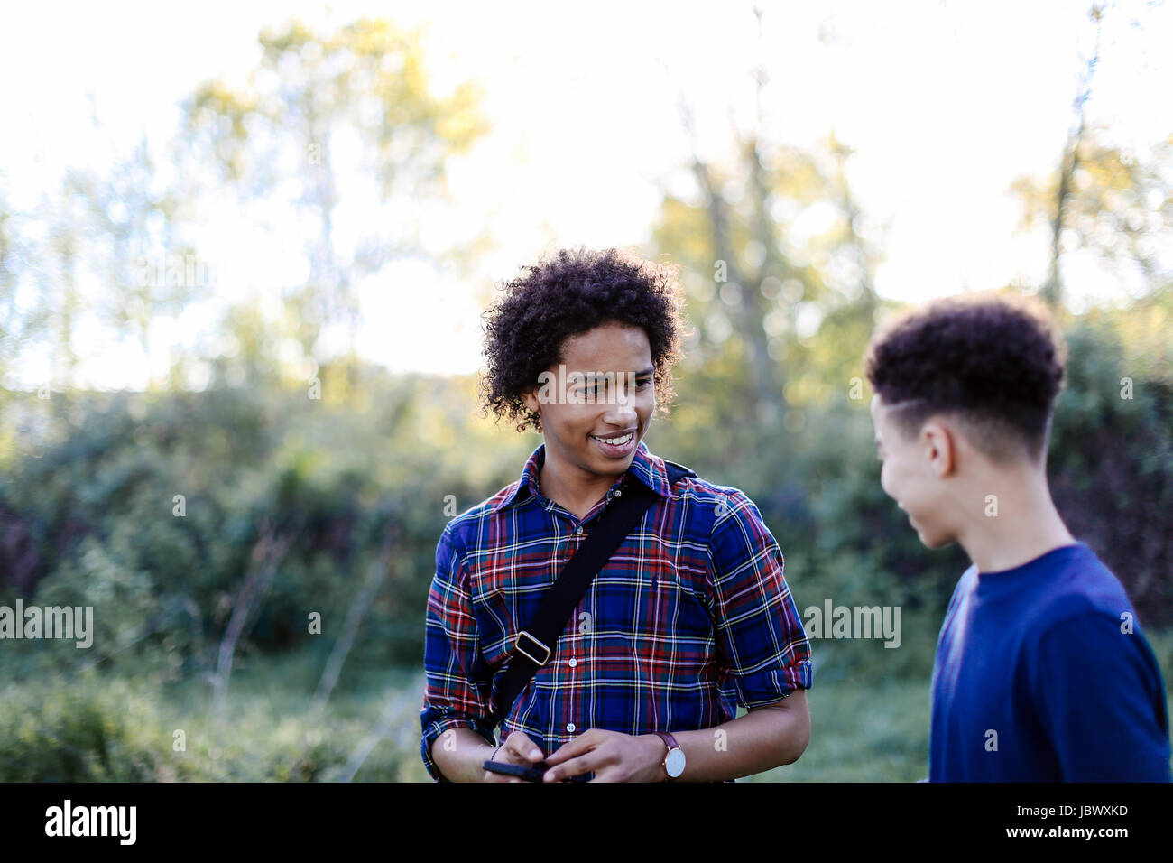 Two male friends, walking through park, having conversation Stock Photo ...