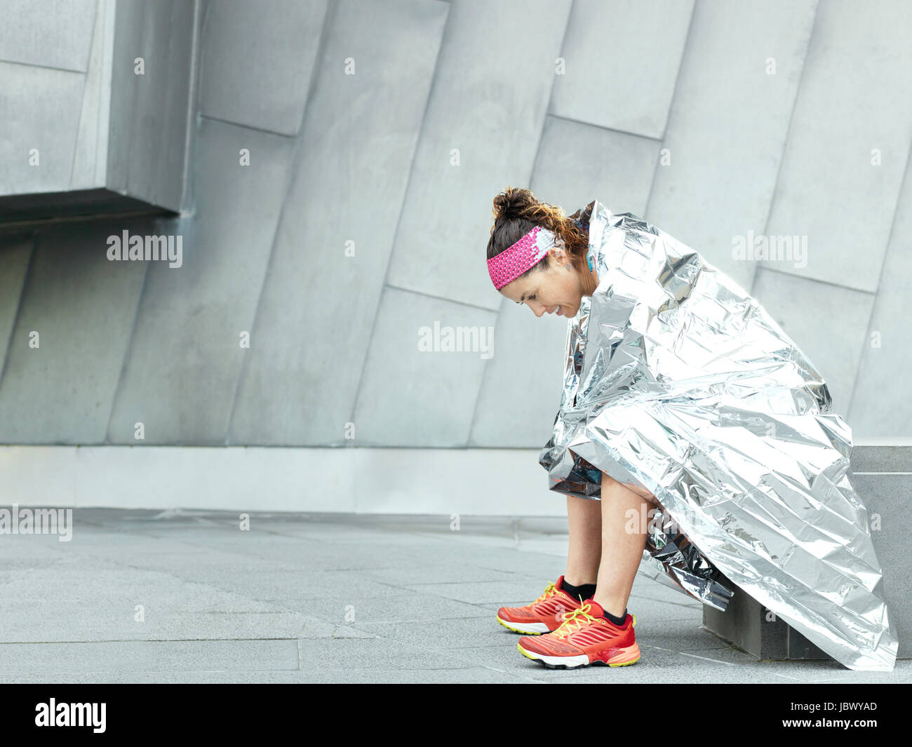 Mature female ultra runner wrapped in foil blanket in city Stock Photo ...