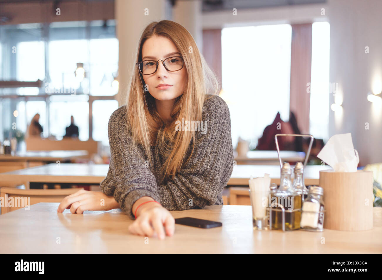 Portrait of cute freelancer girl sitting in a cafe. She wears brown ...