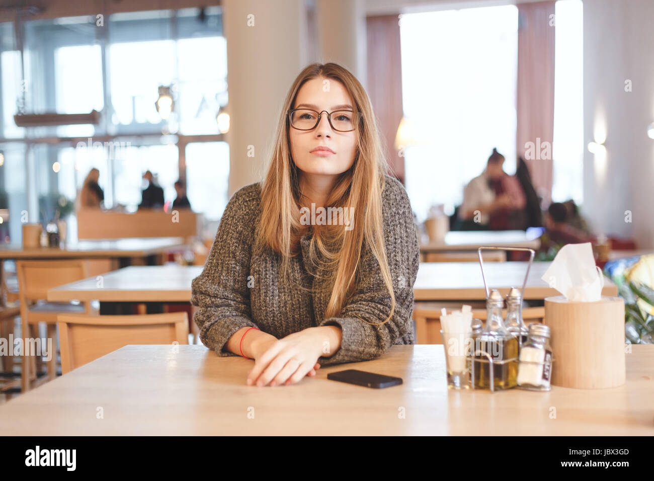 Portrait of cute freelancer girl sitting in a cafe. She wears brown ...