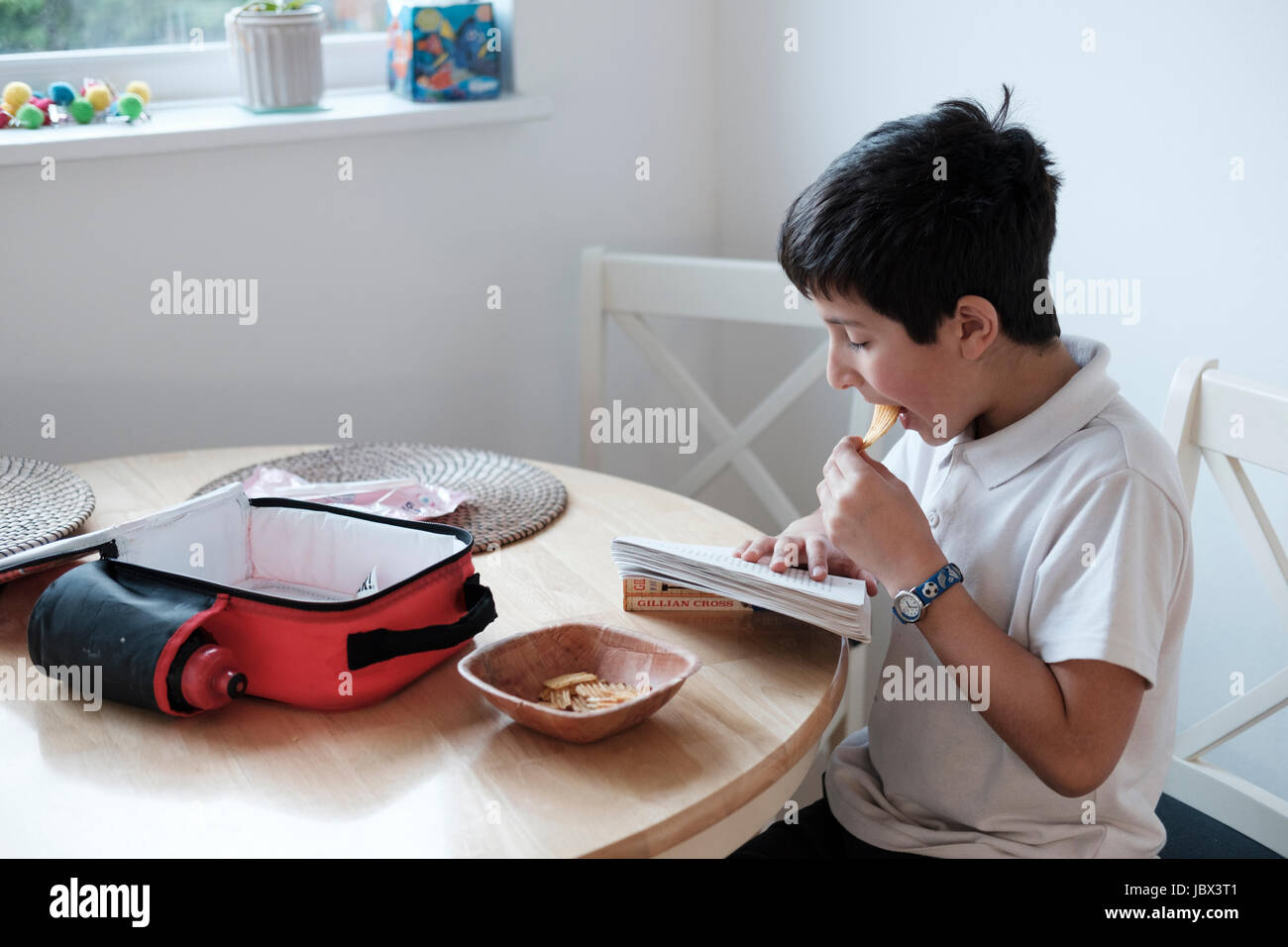 Schoolchild,9-10, reads a book and snaks on crisps,UK Stock Photo - Alamy