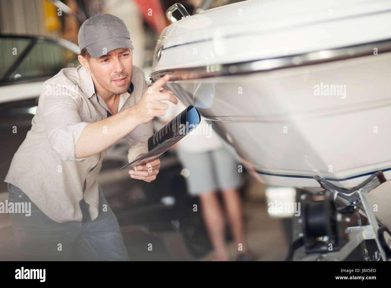 Man checking bodywork on boat in repair workshop Stock Photo - Alamy