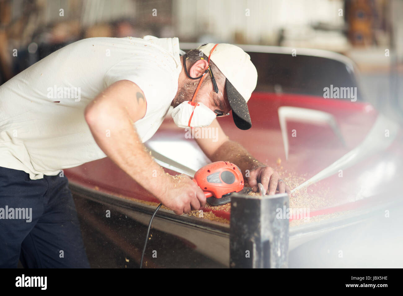 Man sanding bodywork in boat repair workshop Stock Photo - Alamy