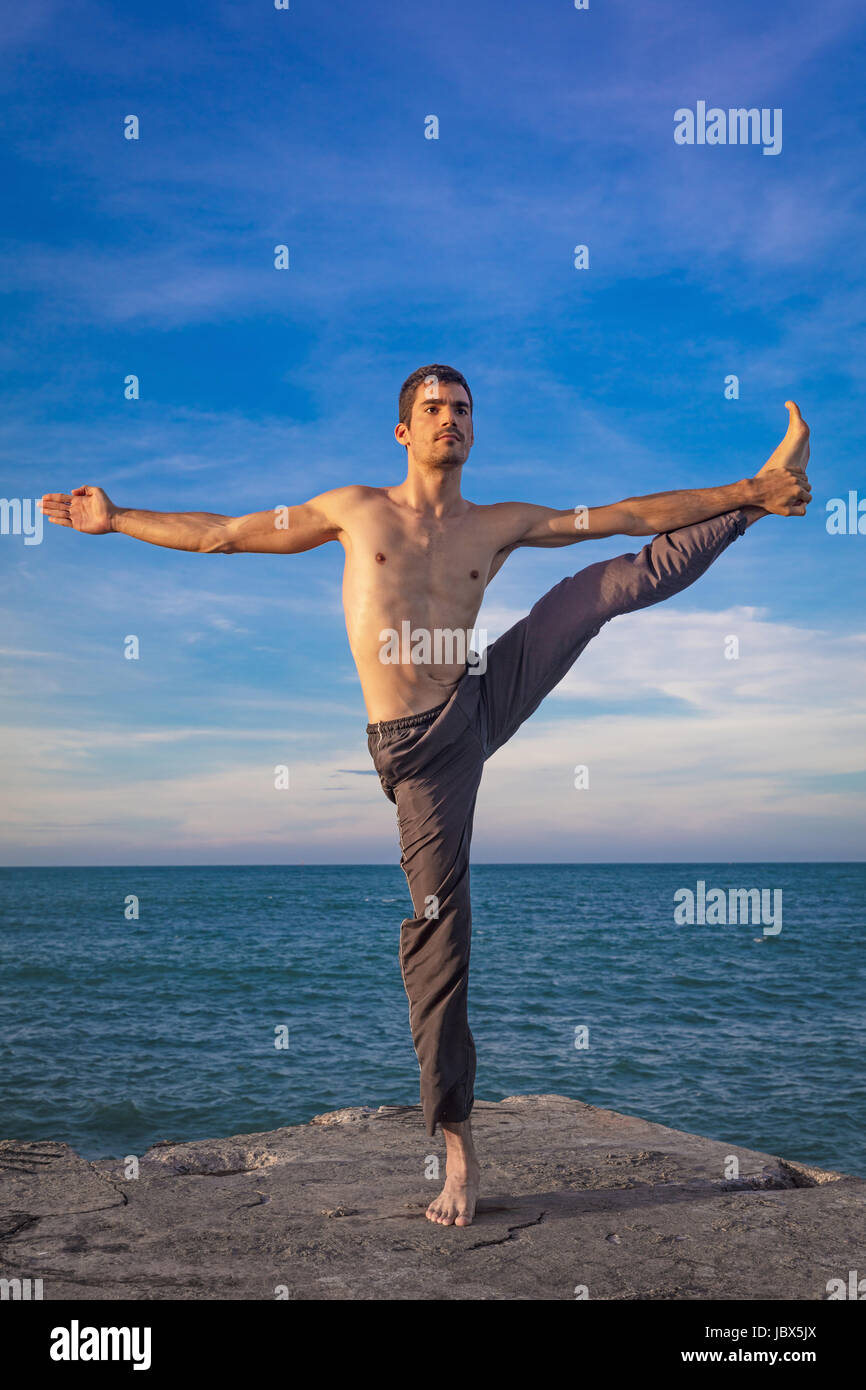 Young man outdoors, in yoga position, balancing on one leg Stock Photo ...