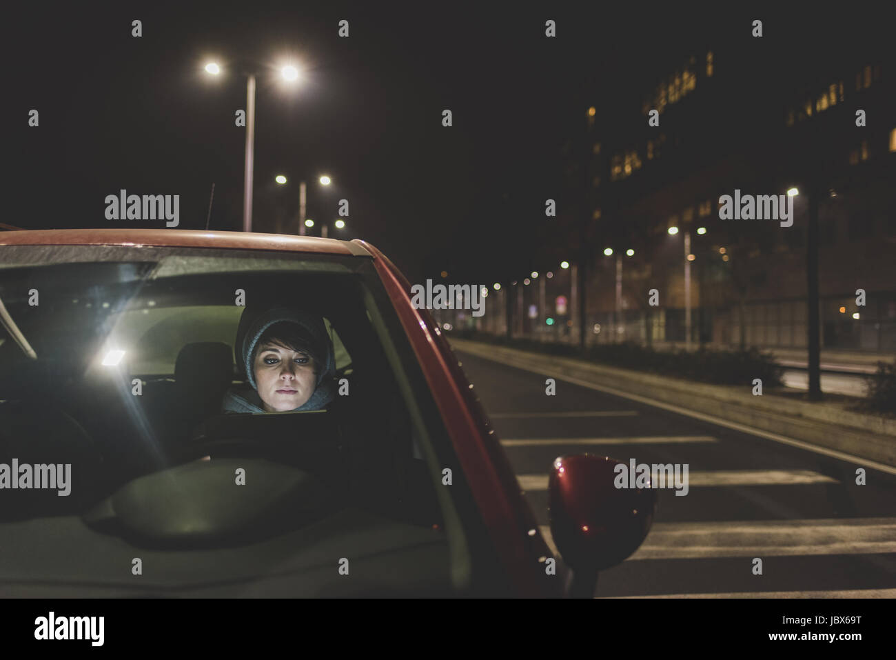 Woman looking out of car windscreen on city roadside at night Stock ...