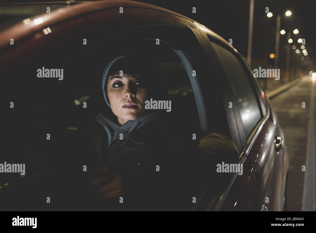 Woman looking out of car window on city roadside at night Stock Photo ...
