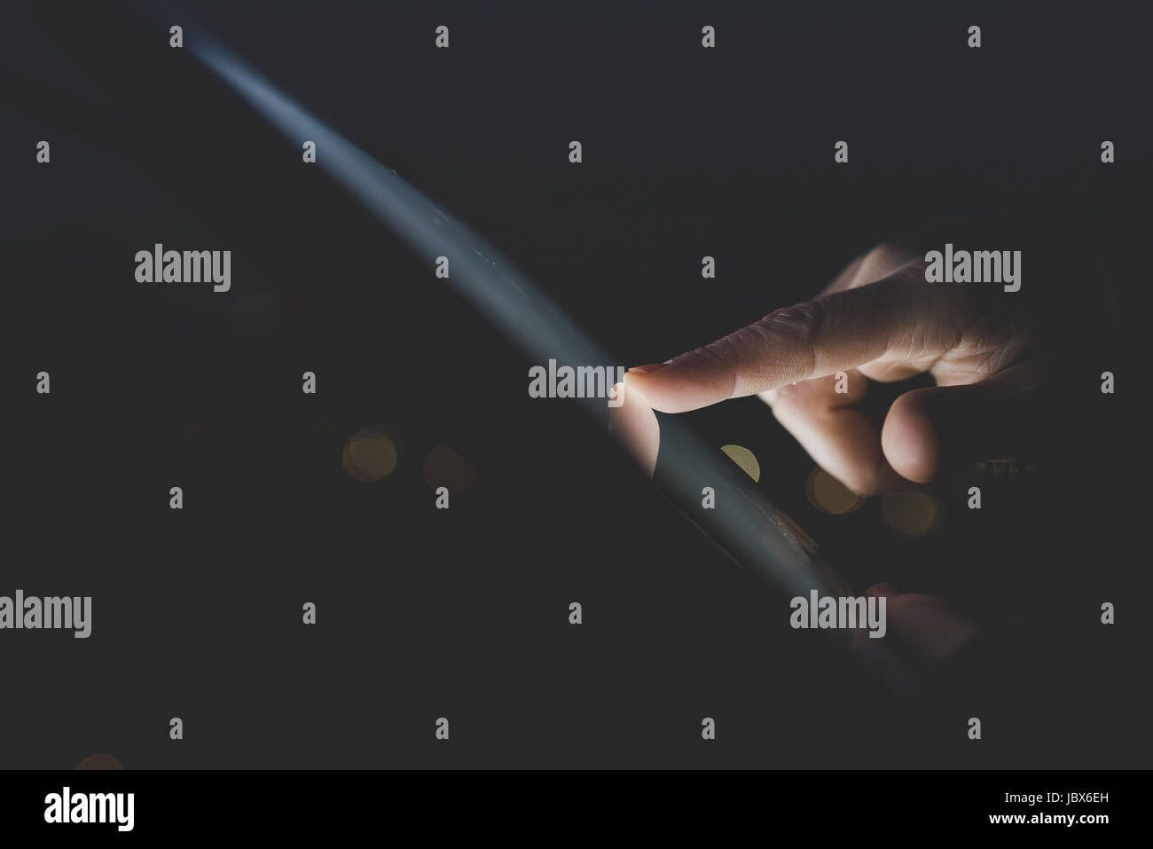 Close up of woman's finger using digital tablet touchscreen in darkness ...