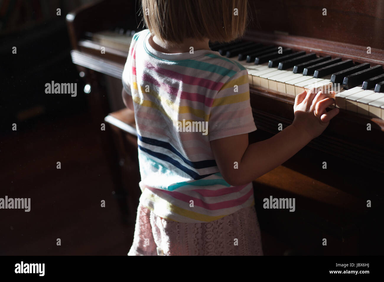 Rear mid section view of girl standing playing old piano at home Stock ...