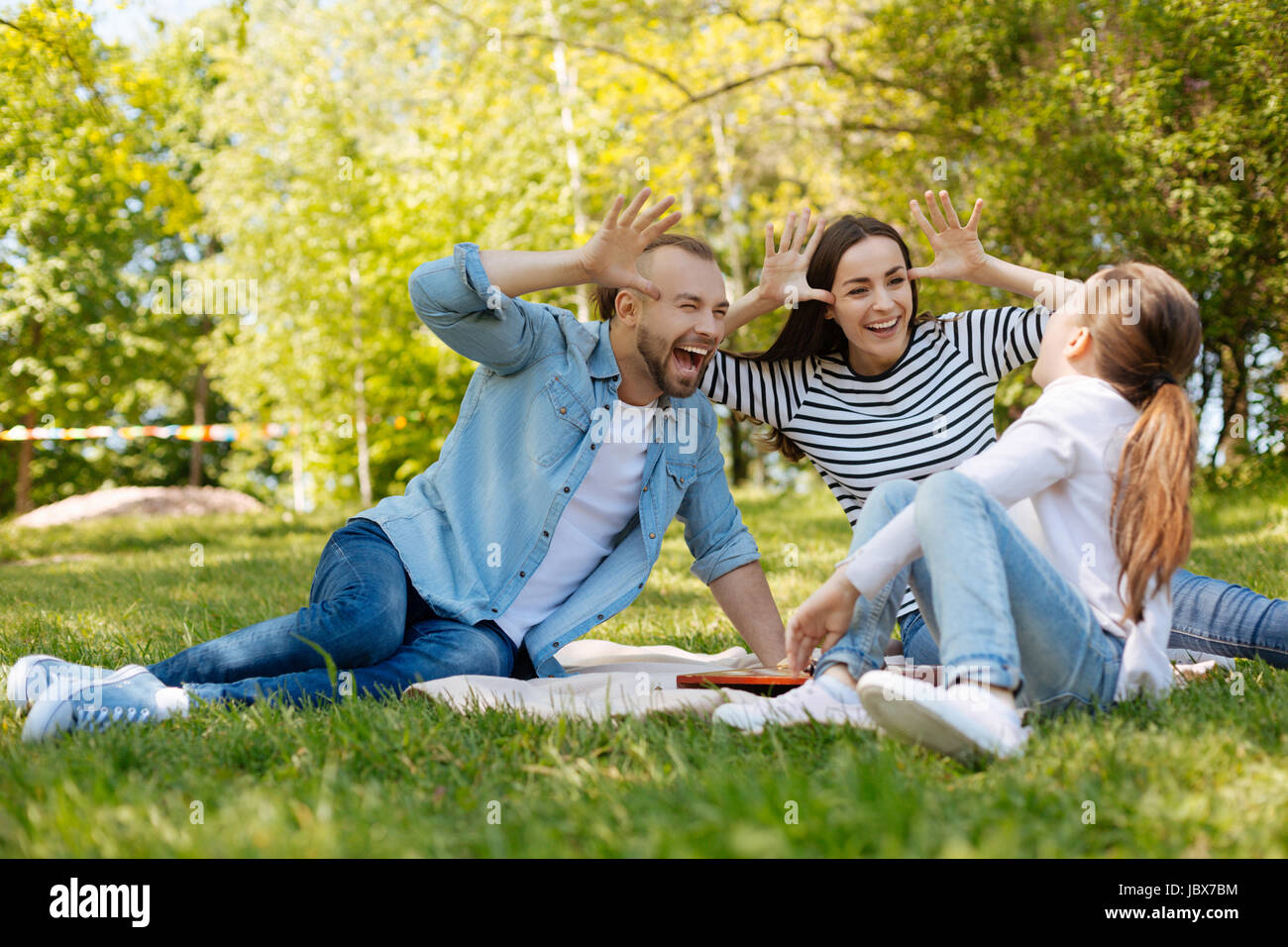 Joyful parents making faces for their daughter Stock Photo - Alamy