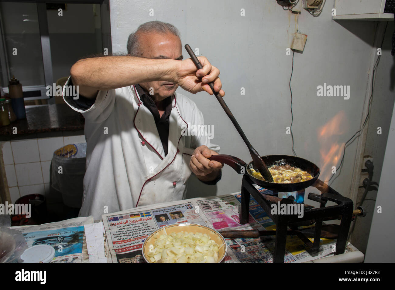 Chef working in a restaurant kitchen frying eggs and lamb Beirut ...