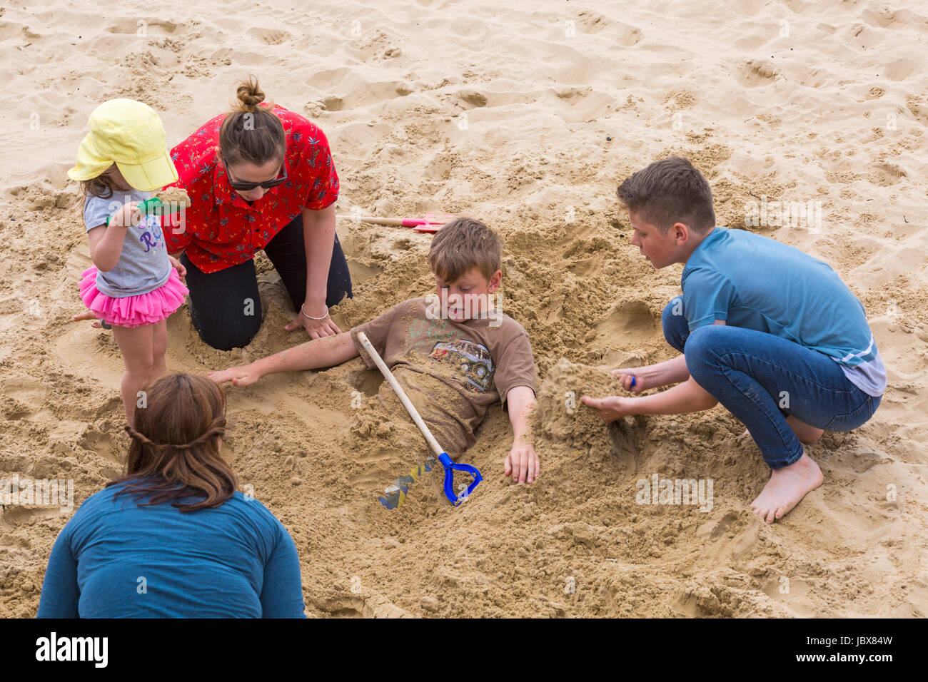Burying boy in the sand at Bournemouth beach, Dorset in June Stock ...