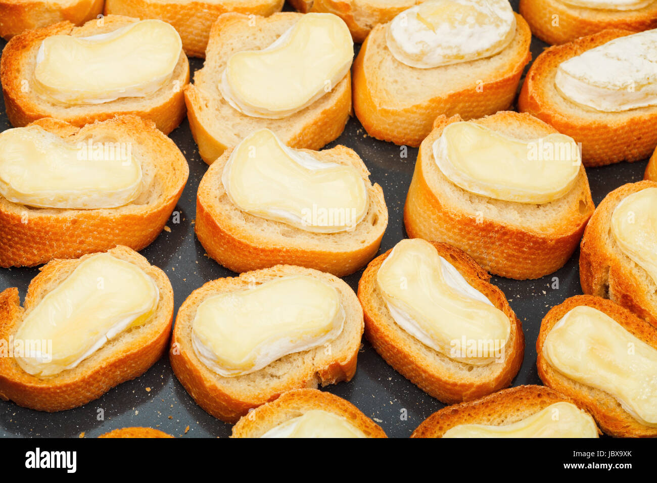 many toasted pieces of bread with melted goat cheese on hot tray Stock ...