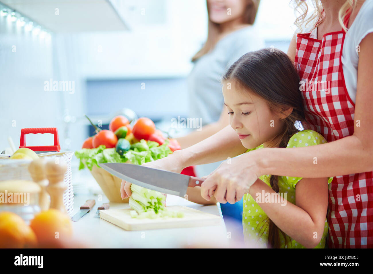 Portrait of little girl helping her mother to cook in the kitchen Stock ...