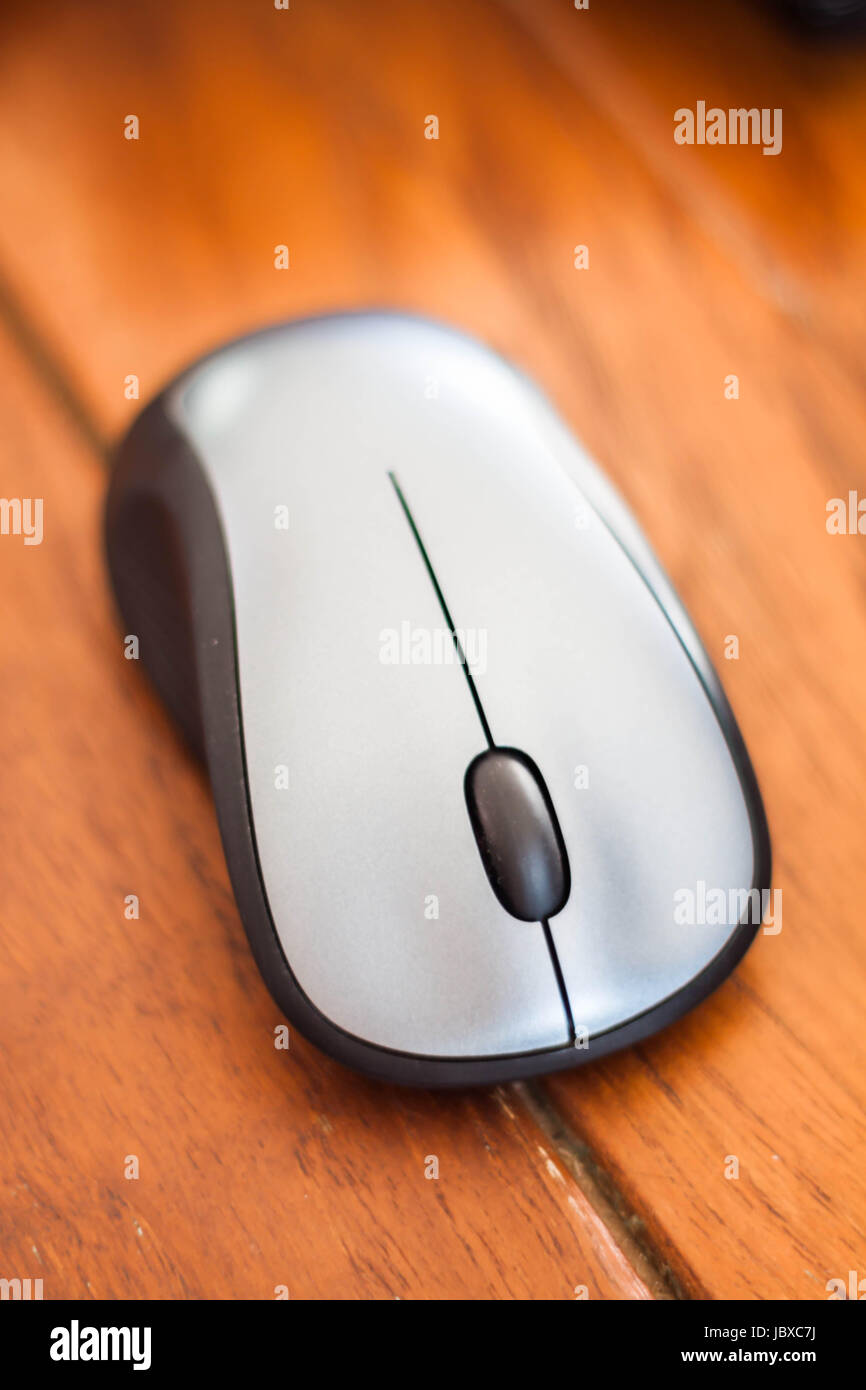 Silver wireless mouse on wood table Stock Photo - Alamy