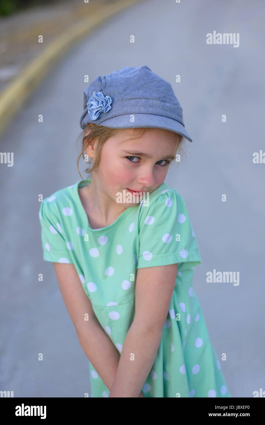Portrait of cute girl in denim cap and green dress Stock Photo - Alamy