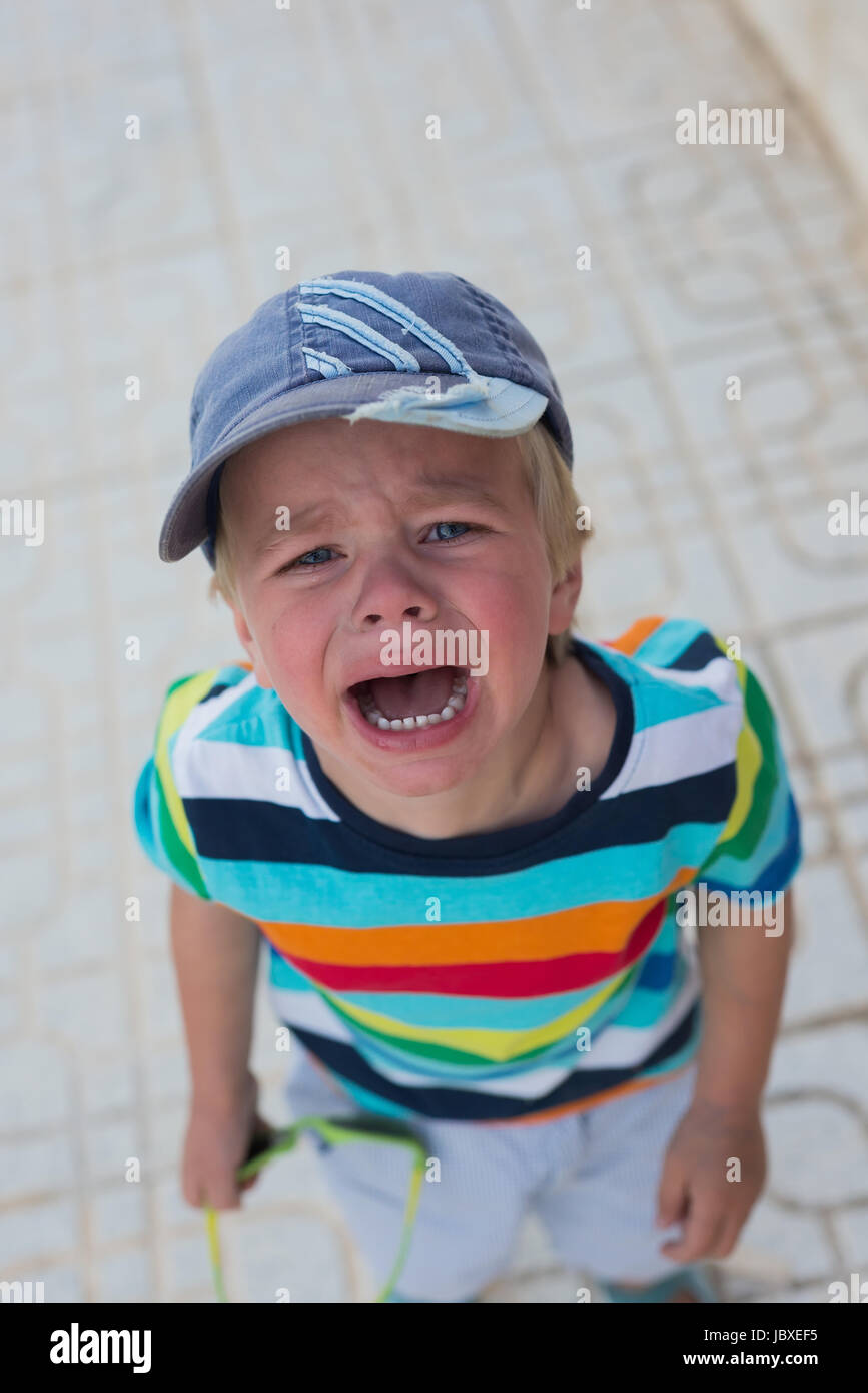 Crying boy standing on the street in town Stock Photo - Alamy